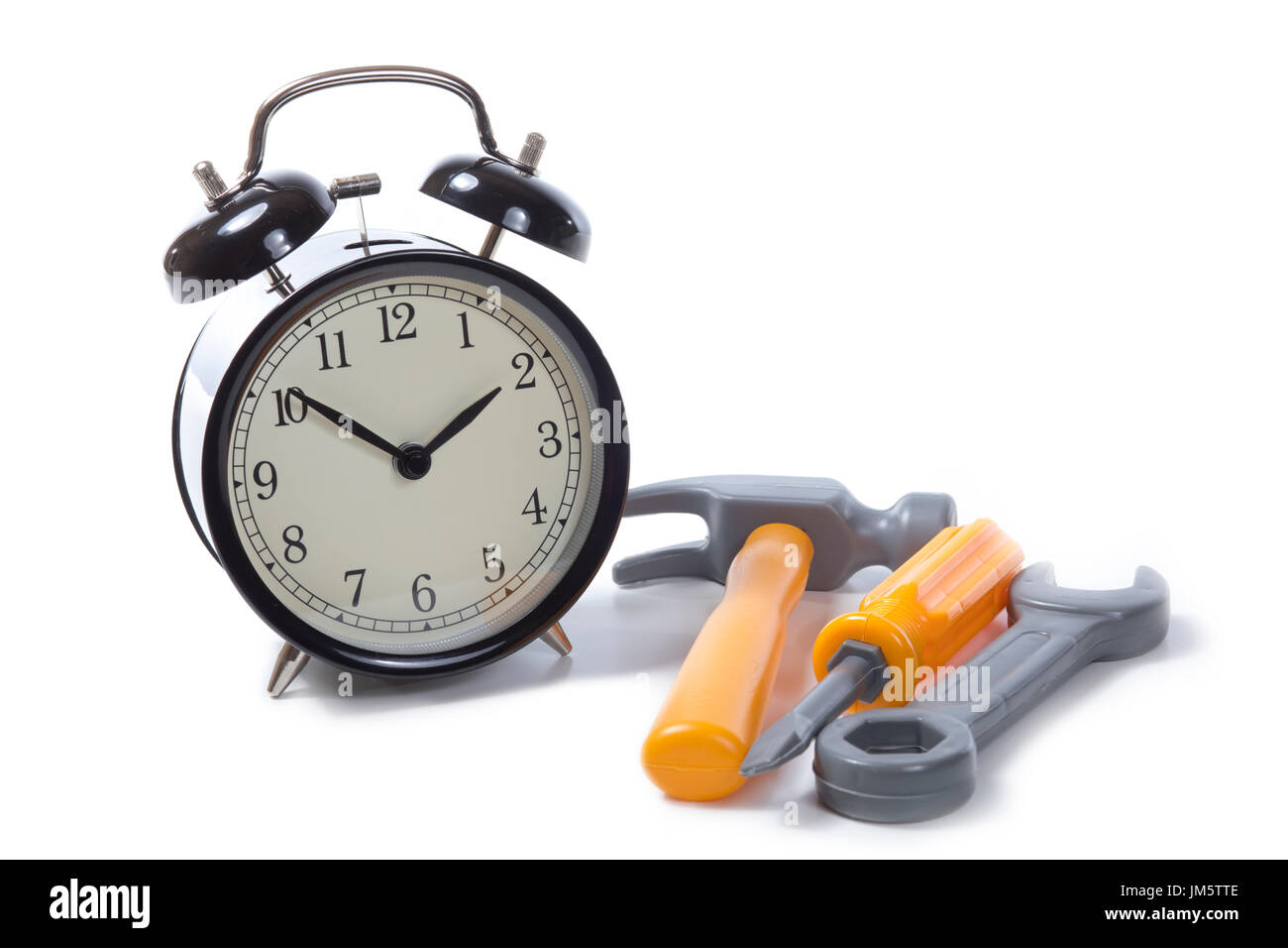 Classic alarm clock with plastic toy tools front view isolated on white ...