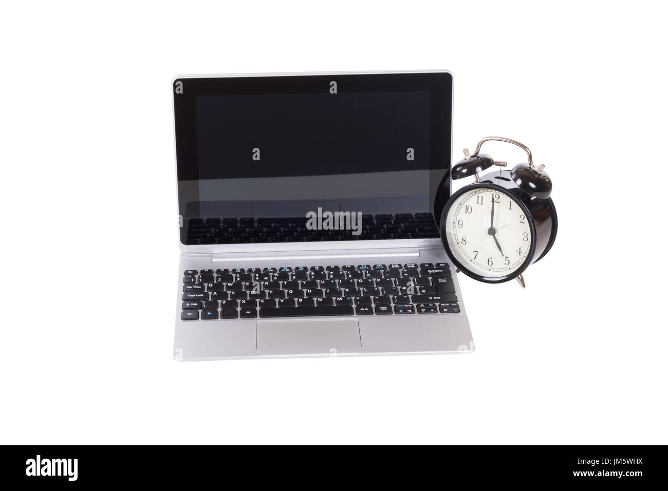 Alarm clock alongside an open laptop computer with a blank screen with ...