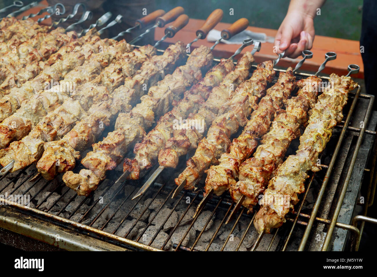 Grilled shish kebab on metal skewer. Chef hands cooking roasted meat ...