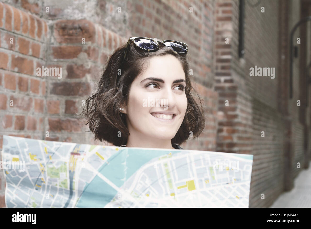 Portrait of a young beautiful tourist looking at a map. Tourism concept ...