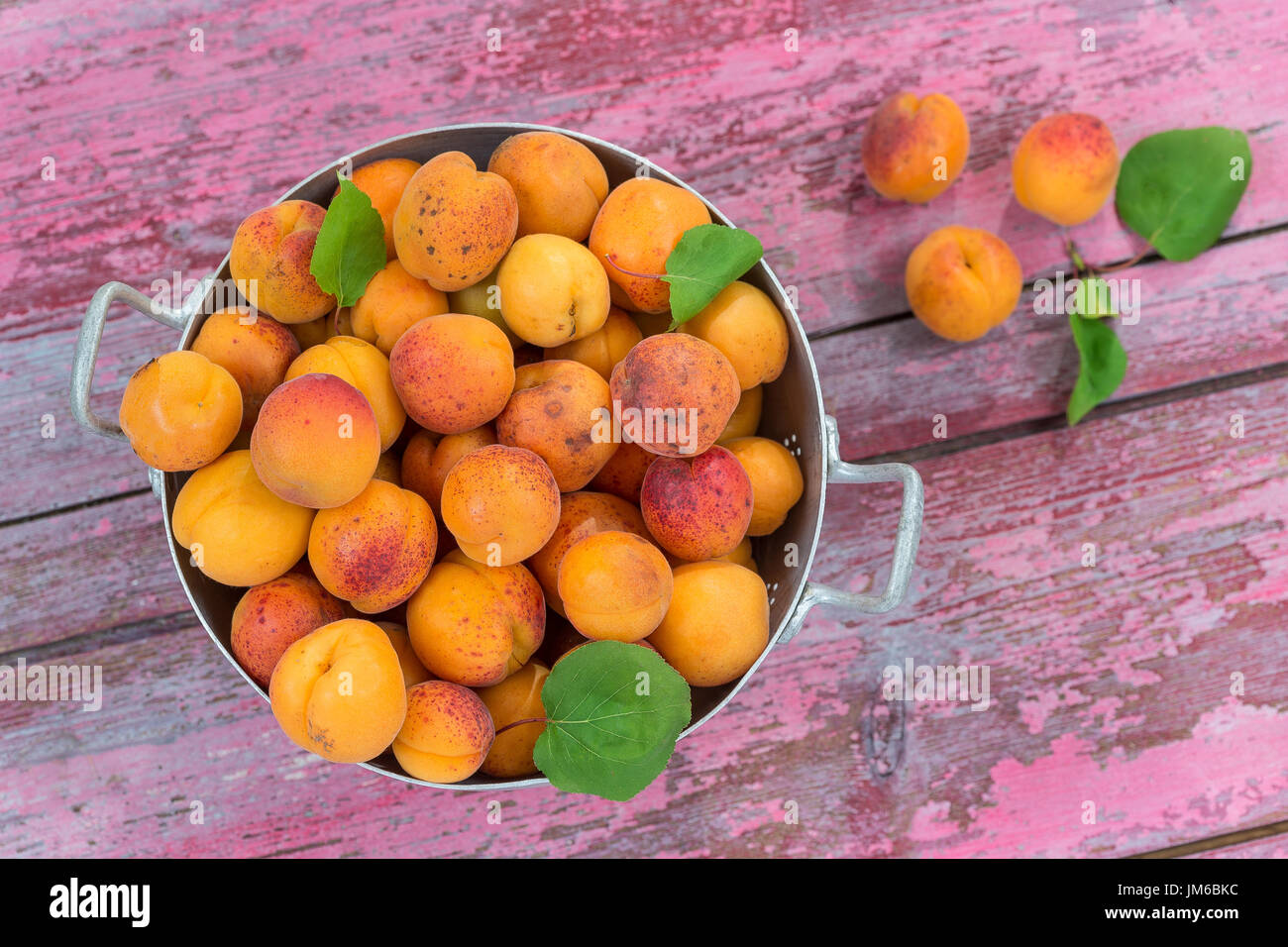 Top view of a vintage sieve with apricots on a old wooden background ...