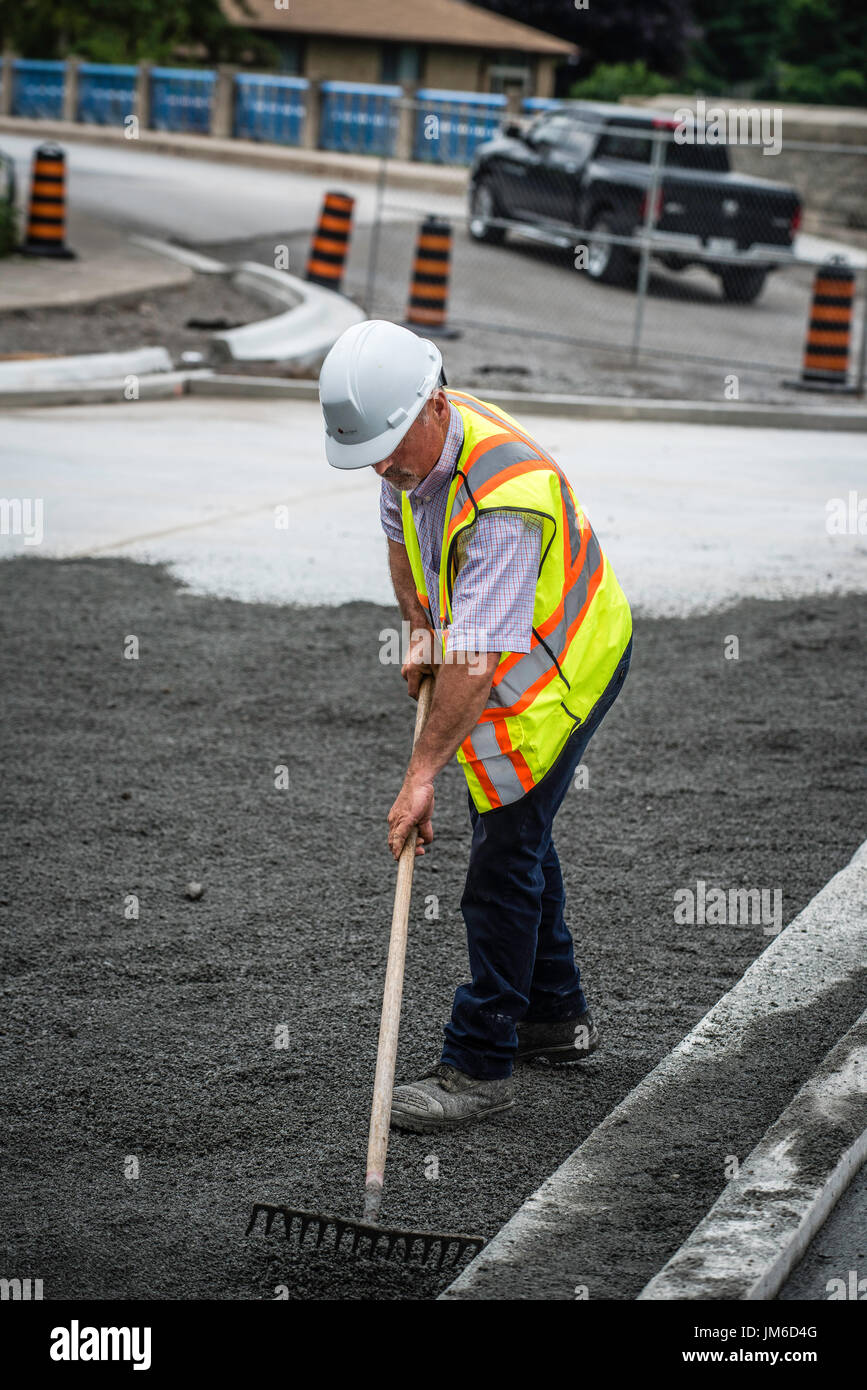 Canadian industrial construction workers laying paving on streets in ...