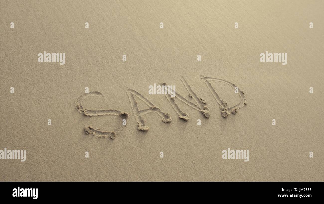SAND written on the beach sand washed aways by waves Stock Photo - Alamy