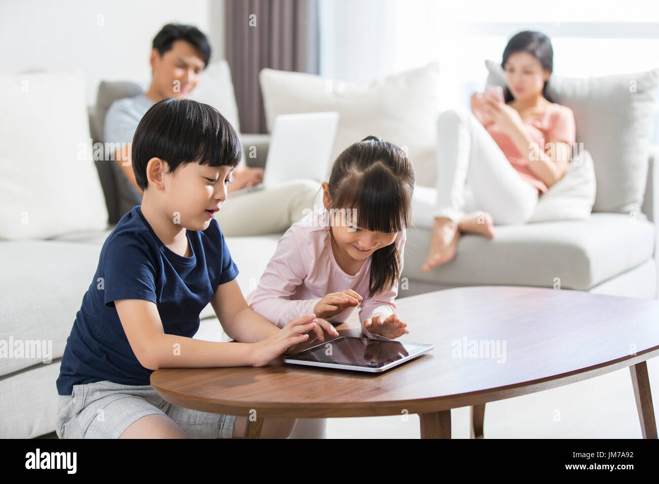 Happy young Chinese family using digital gadgets at home Stock Photo ...