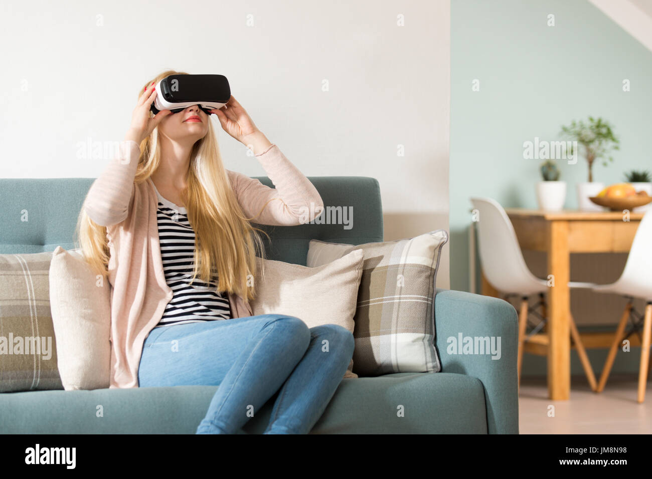 Attractive woman wearing virtual reality glasses lying on a couch ...