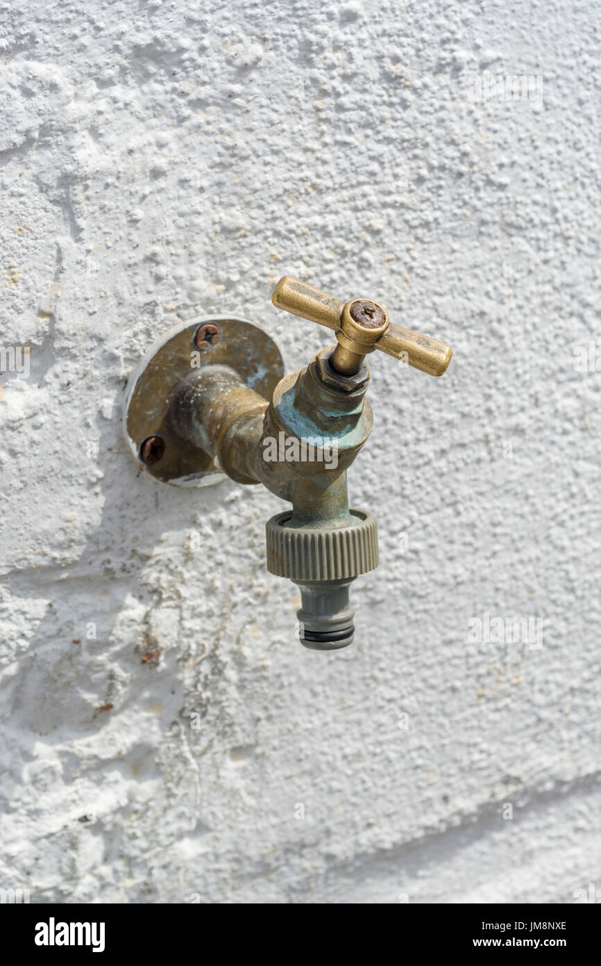 Brass wall tap / garden tap / outside tap seen against whitewashed ...