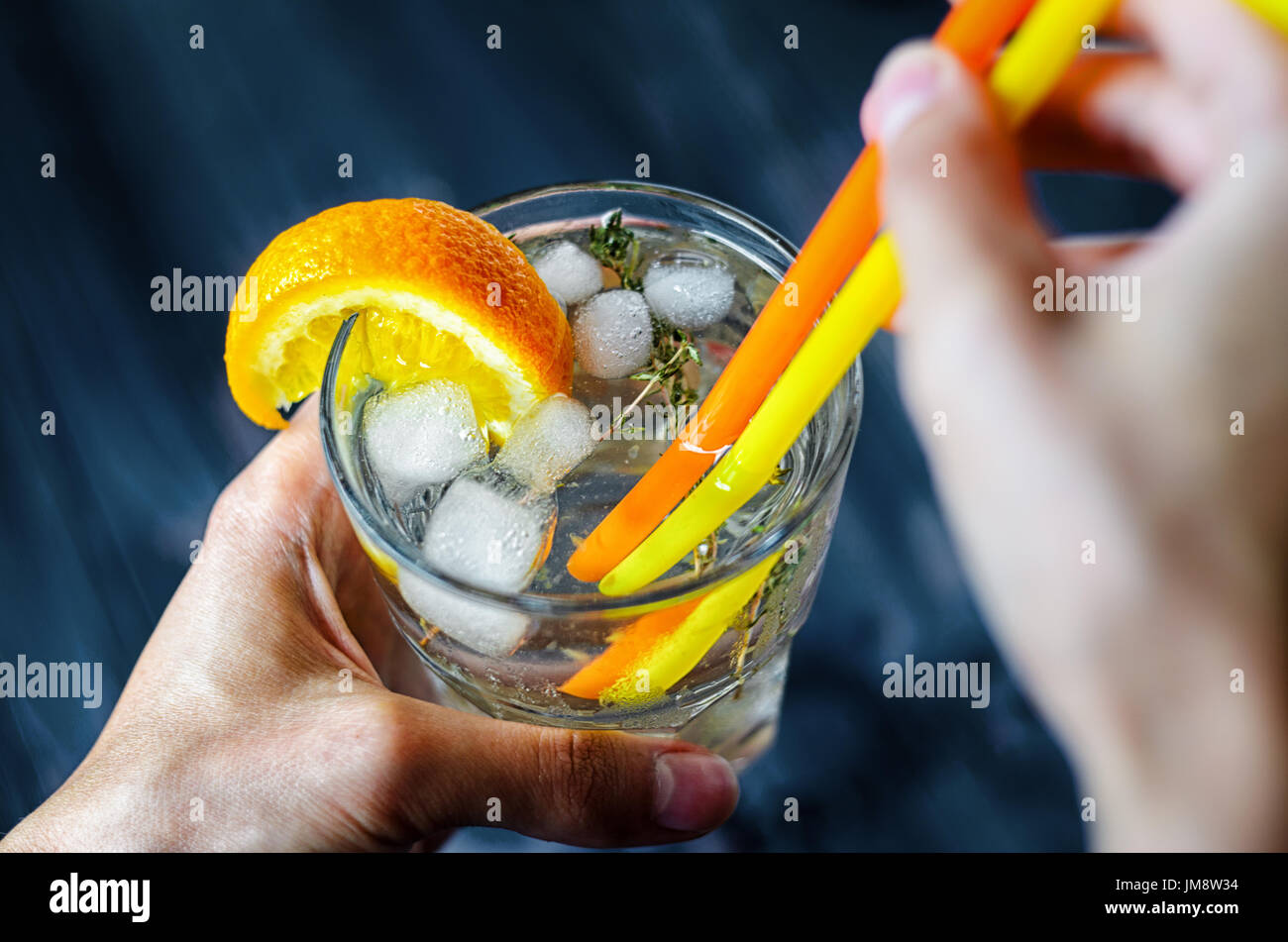 Gin tonic with ice, decorated with an orange slice and rosemary. First ...