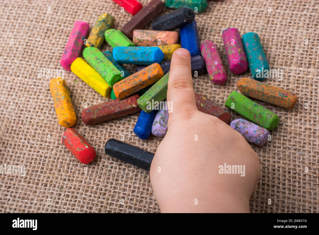 Used color crayons and a toddlers hand on canvas Stock Photo - Alamy