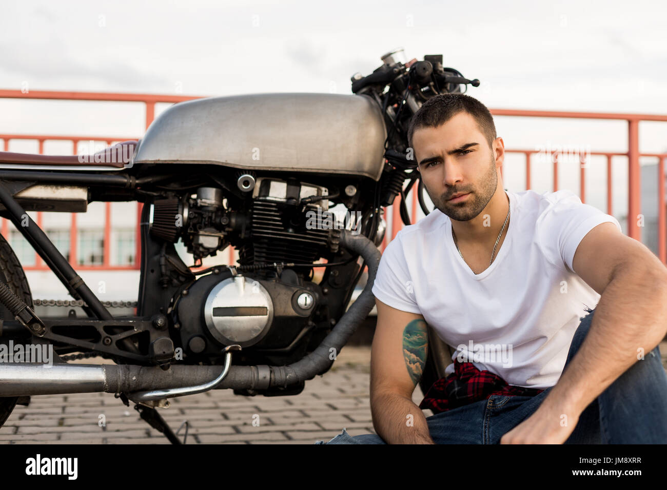 Handsome happy rider man with beard and mustache sit near his classic ...