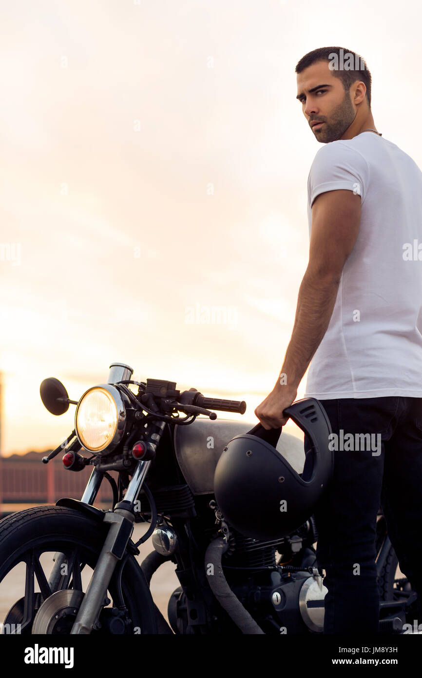 Sporty biker handsome rider male in white t-shirt go travel on classic ...