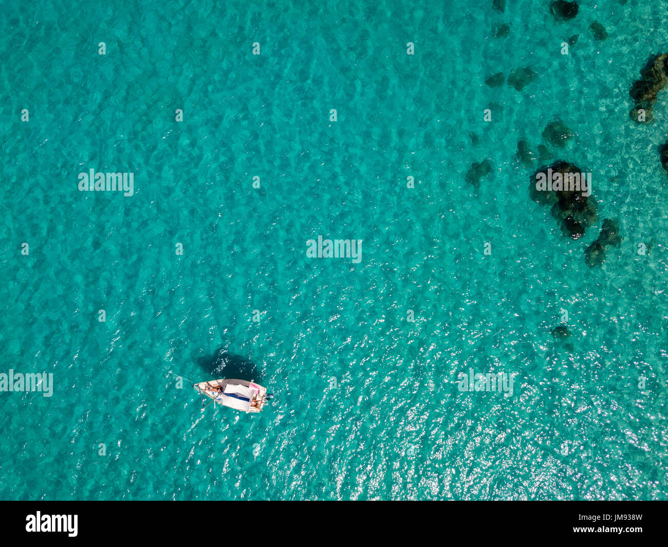 Aerial view of a moored boat floating on a transparent sea. Diving ...