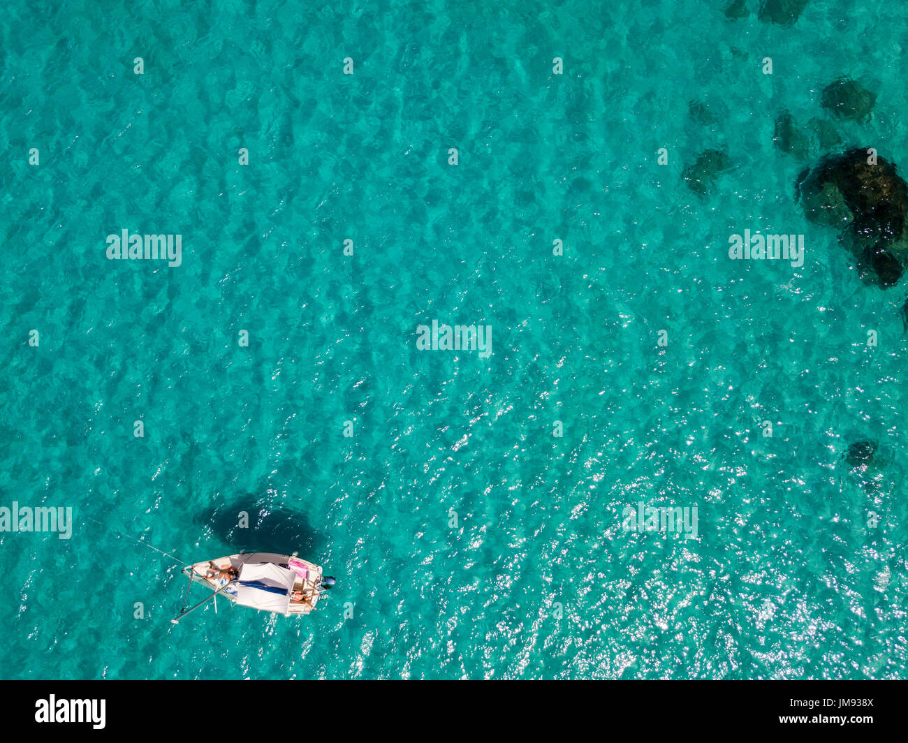 Aerial view of a moored boat floating on a transparent sea. Diving ...