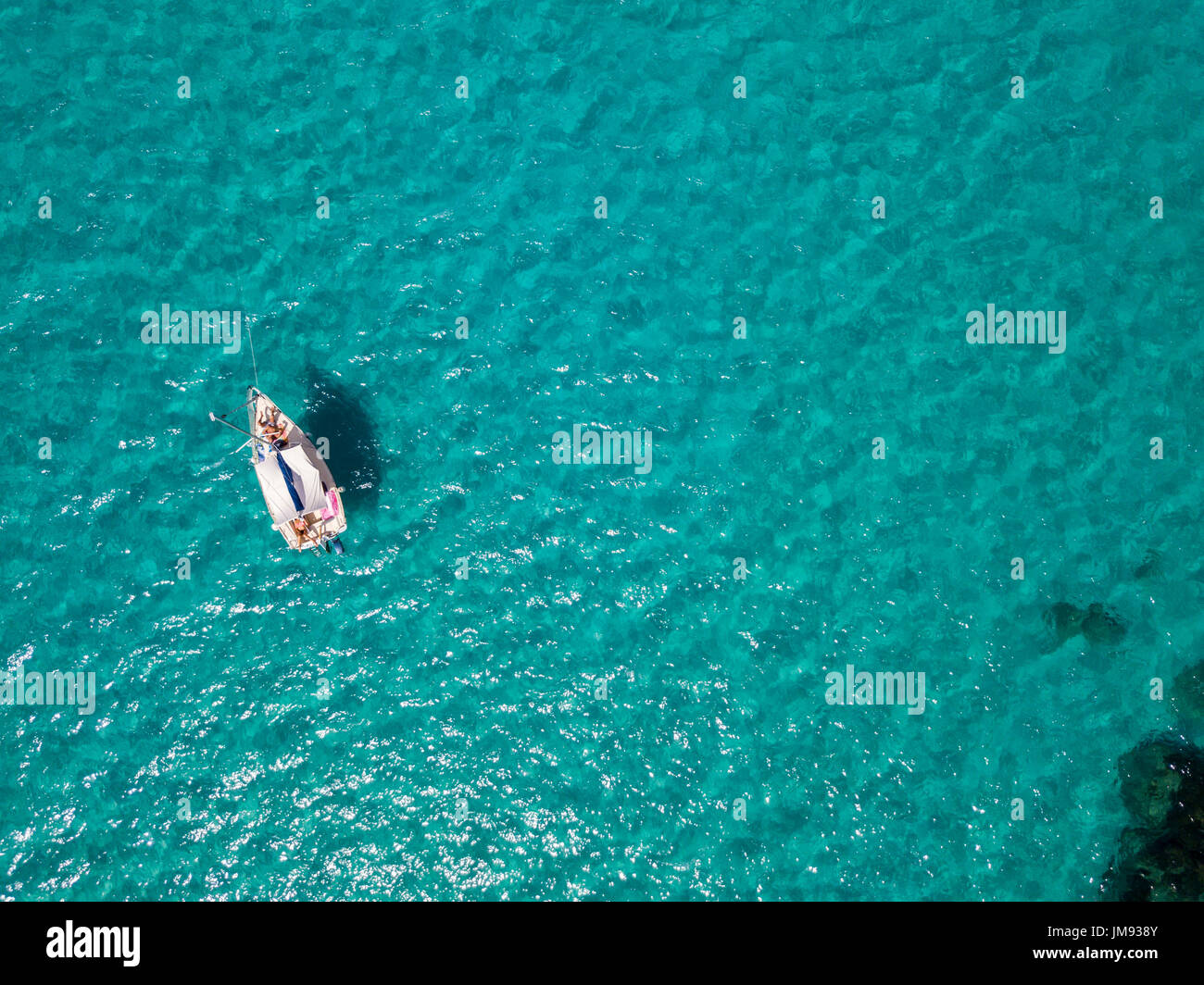 Aerial view of a moored boat floating on a transparent sea. Diving ...
