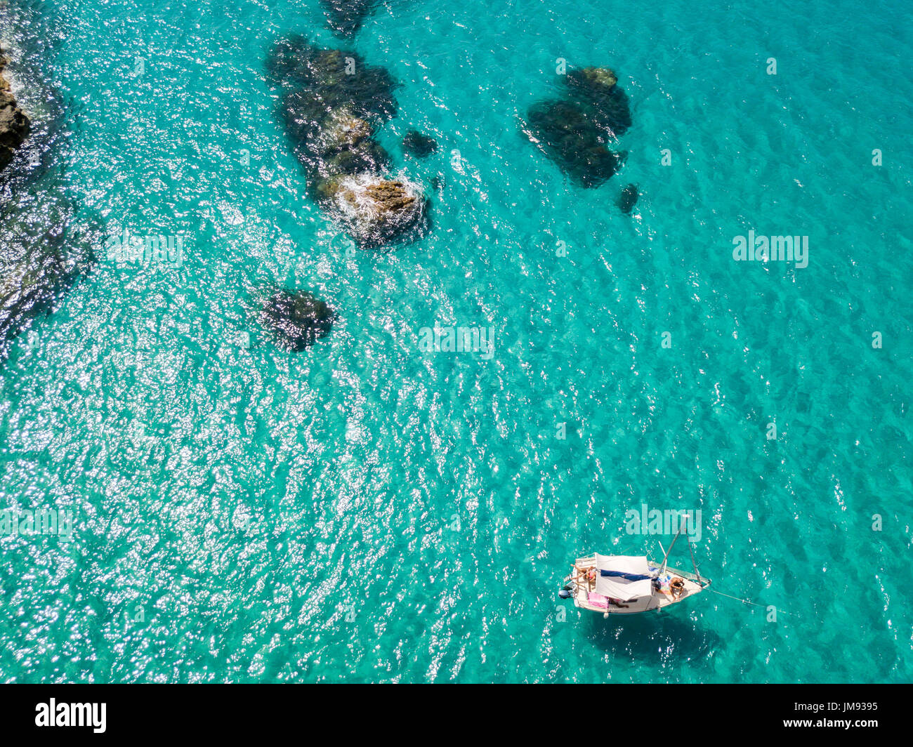 Aerial view of a moored boat floating on a transparent sea. Diving ...