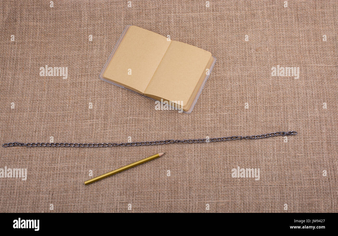 Pencil and notebook with a chain in the middle on spiral notebooks ...