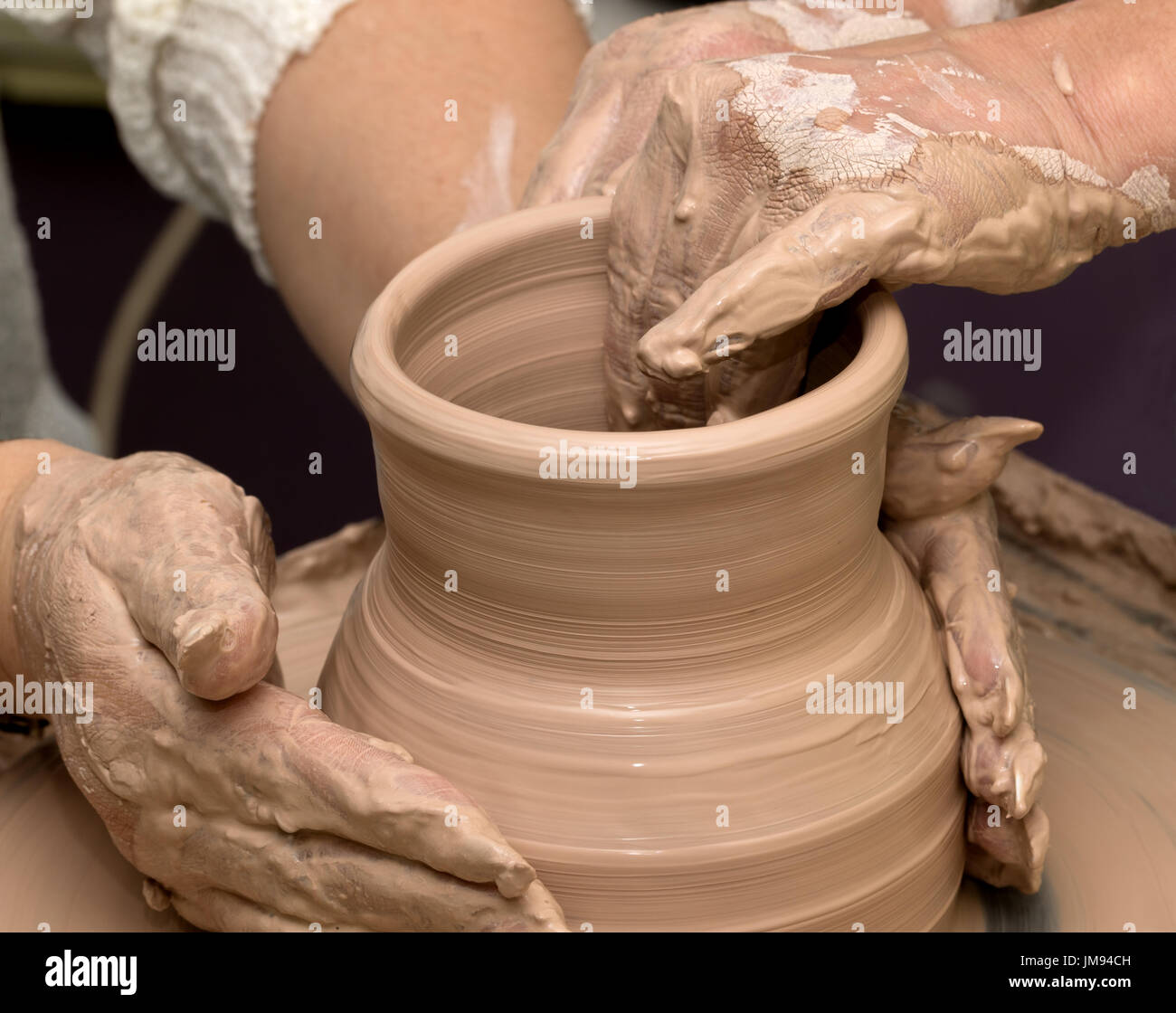 Two women in process of making clay vase on pottery wheel. Potters at ...