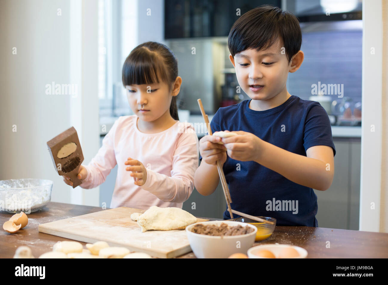 Happy Chinese siblings baking together Stock Photo - Alamy