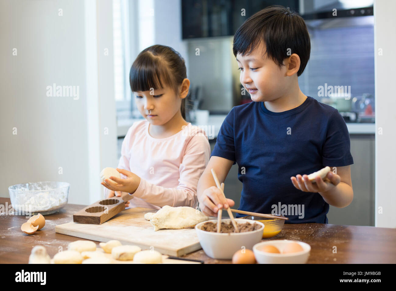 Happy Chinese siblings baking together Stock Photo - Alamy