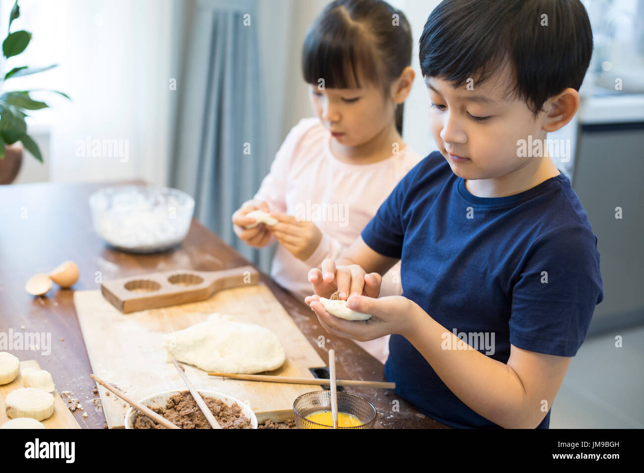 Happy Chinese siblings baking together Stock Photo - Alamy