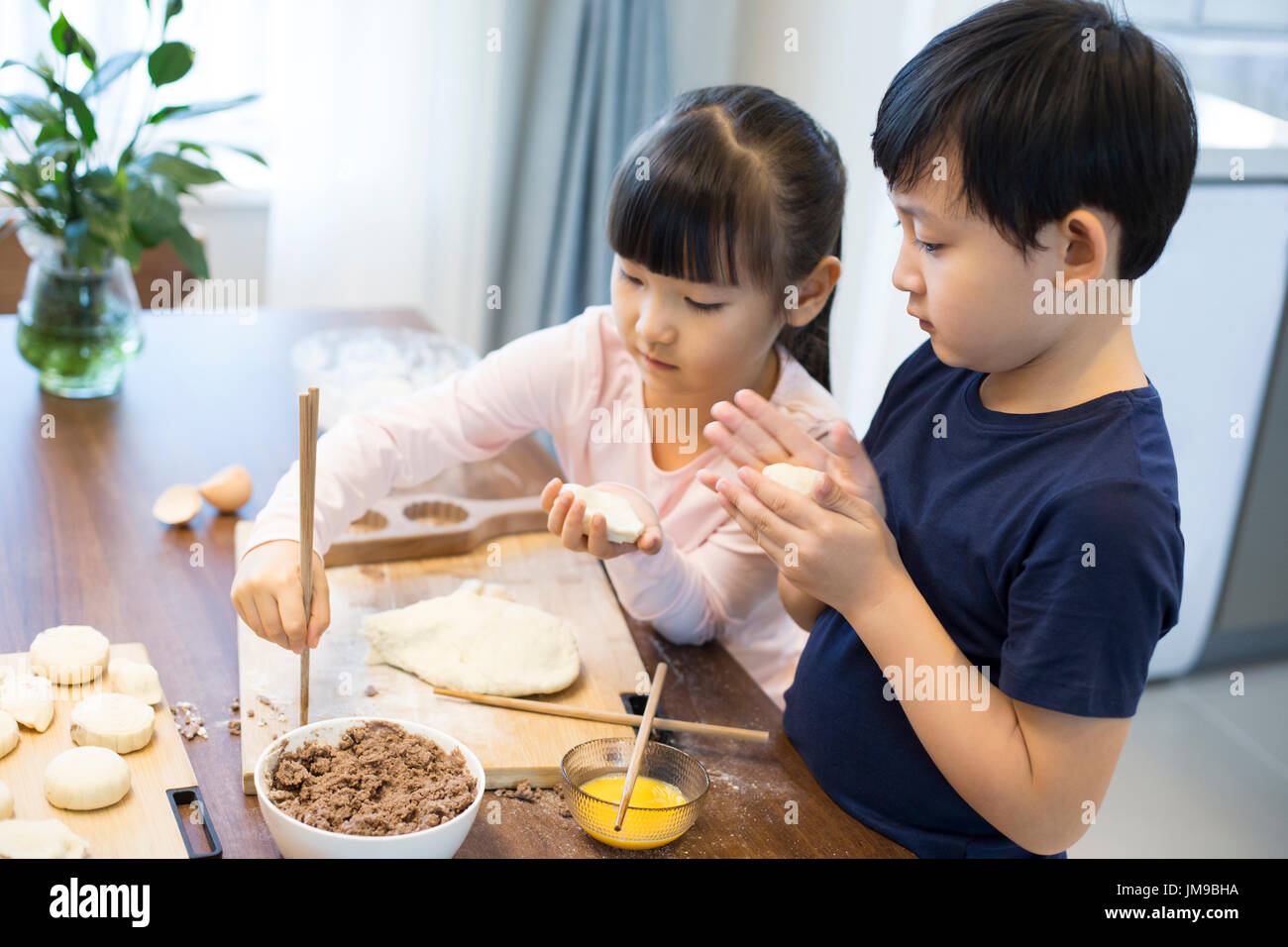 Happy Chinese siblings baking together Stock Photo - Alamy