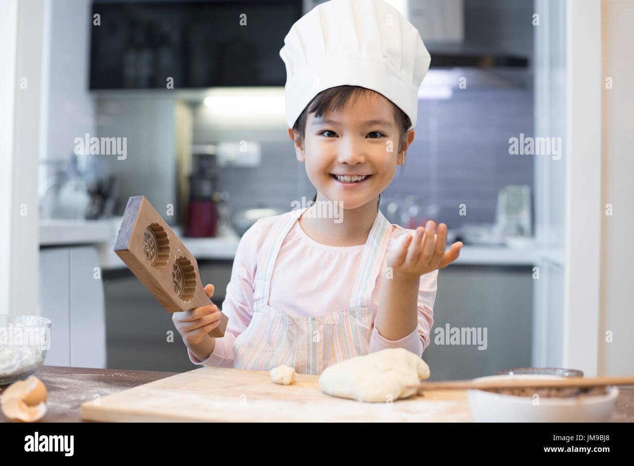 Happy little Chinese girl baking at home Stock Photo - Alamy
