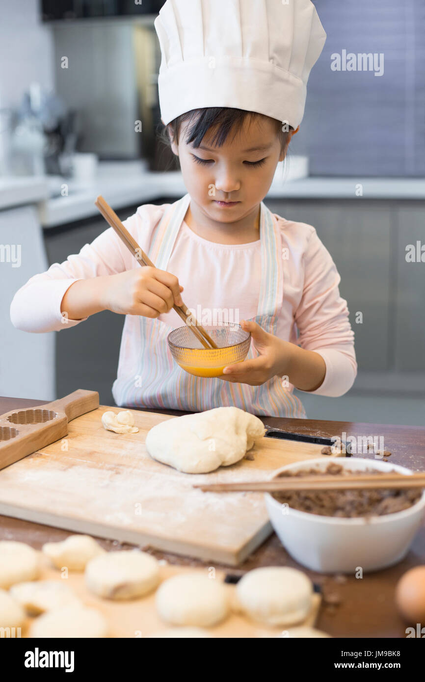 Happy little Chinese girl baking at home Stock Photo - Alamy