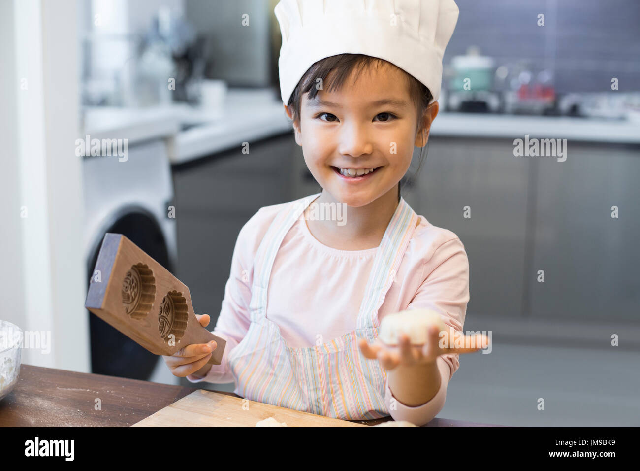 Happy little Chinese girl baking at home Stock Photo - Alamy