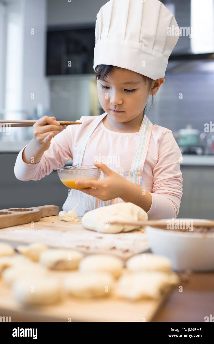 Happy little Chinese girl baking at home Stock Photo - Alamy