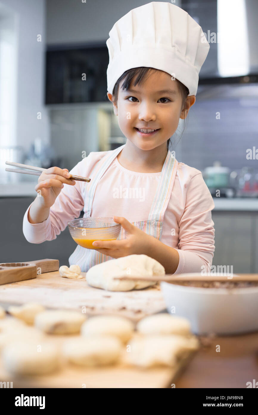 Happy little Chinese girl baking at home Stock Photo - Alamy