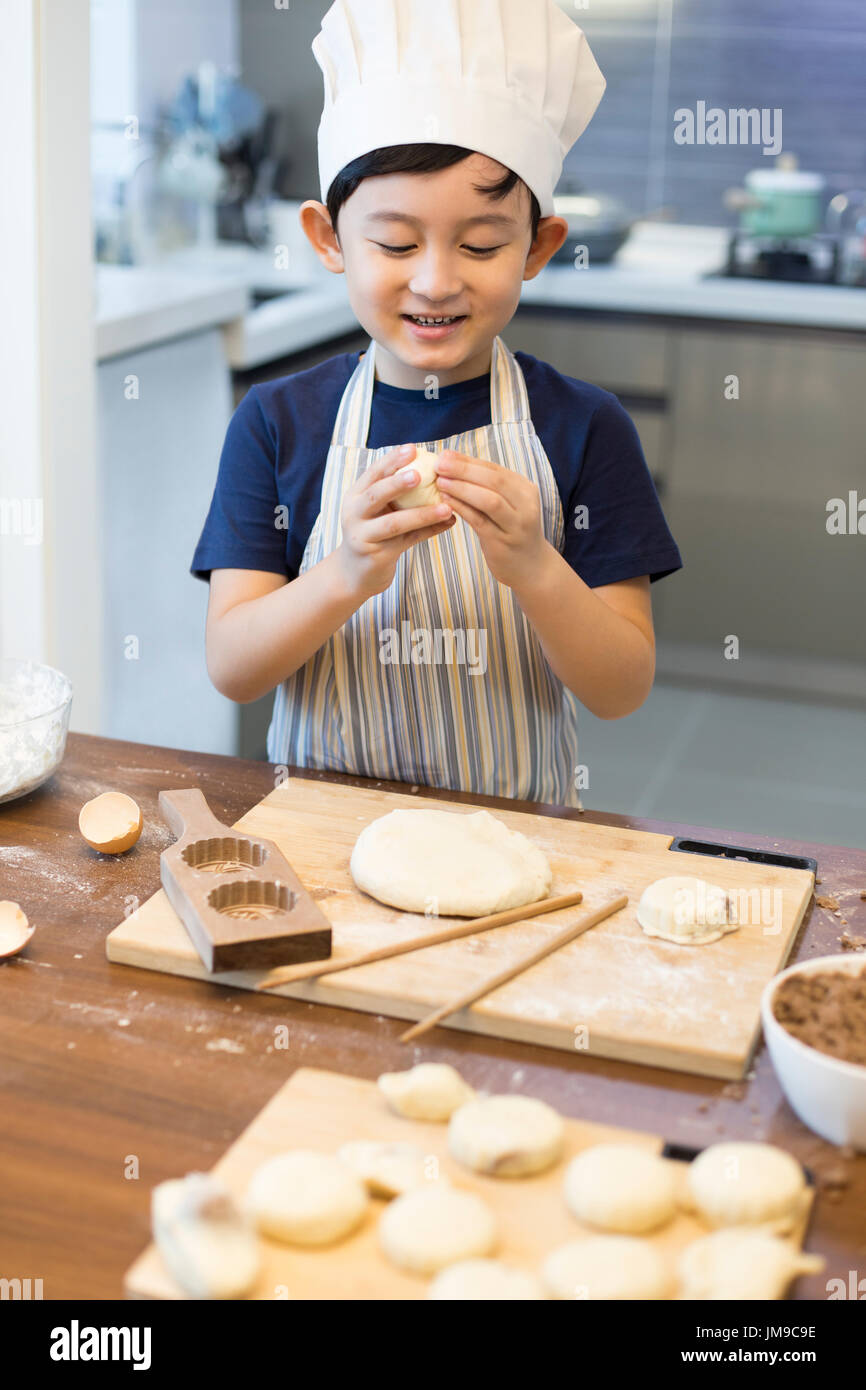 Happy little Chinese boy baking at home Stock Photo - Alamy