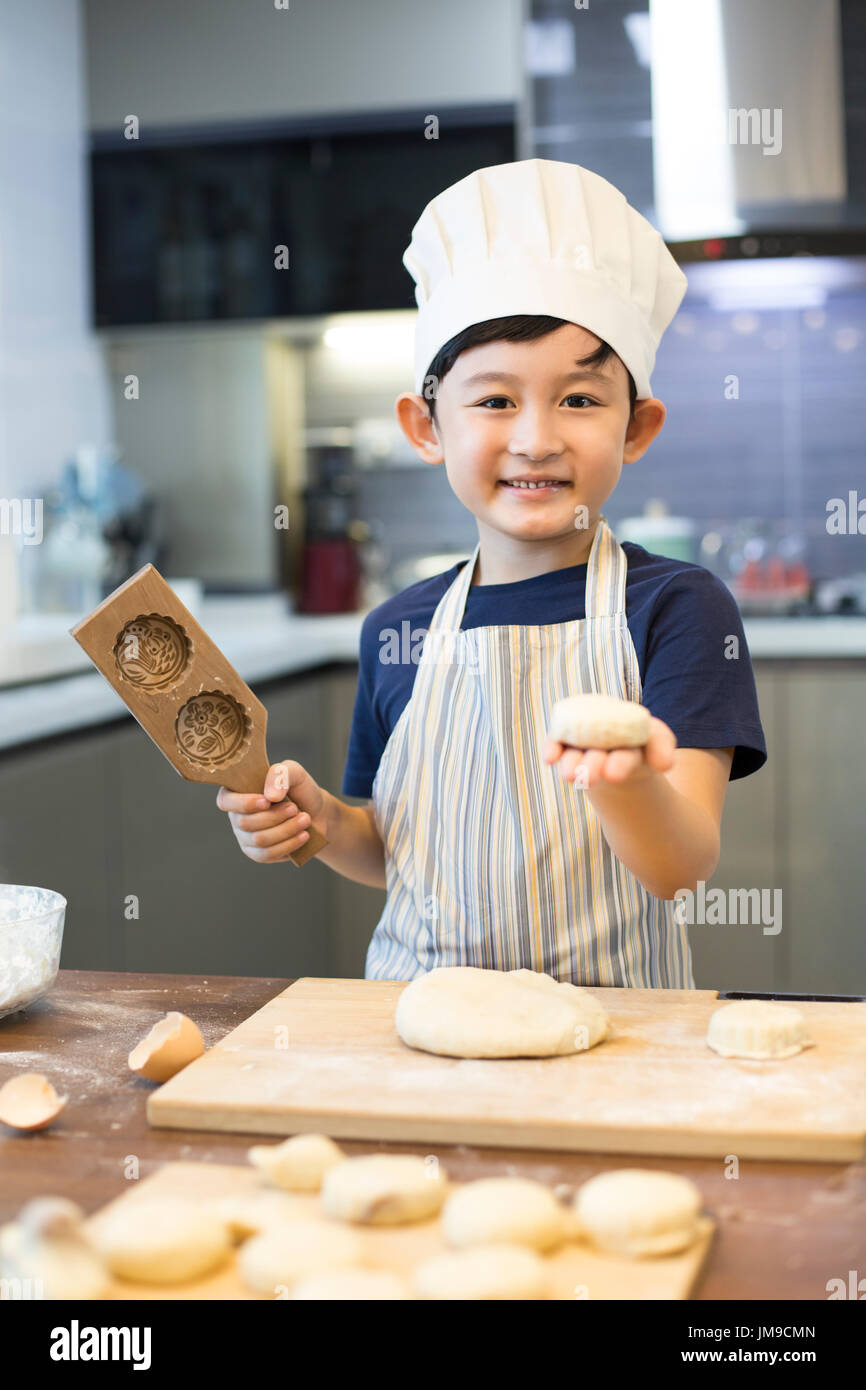 Happy little Chinese boy baking at home Stock Photo - Alamy