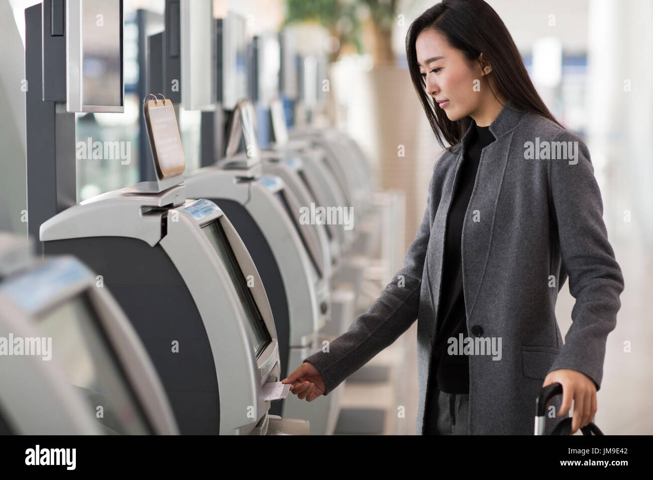 Chinese businesswoman using ticket machine at the airport Stock Photo ...
