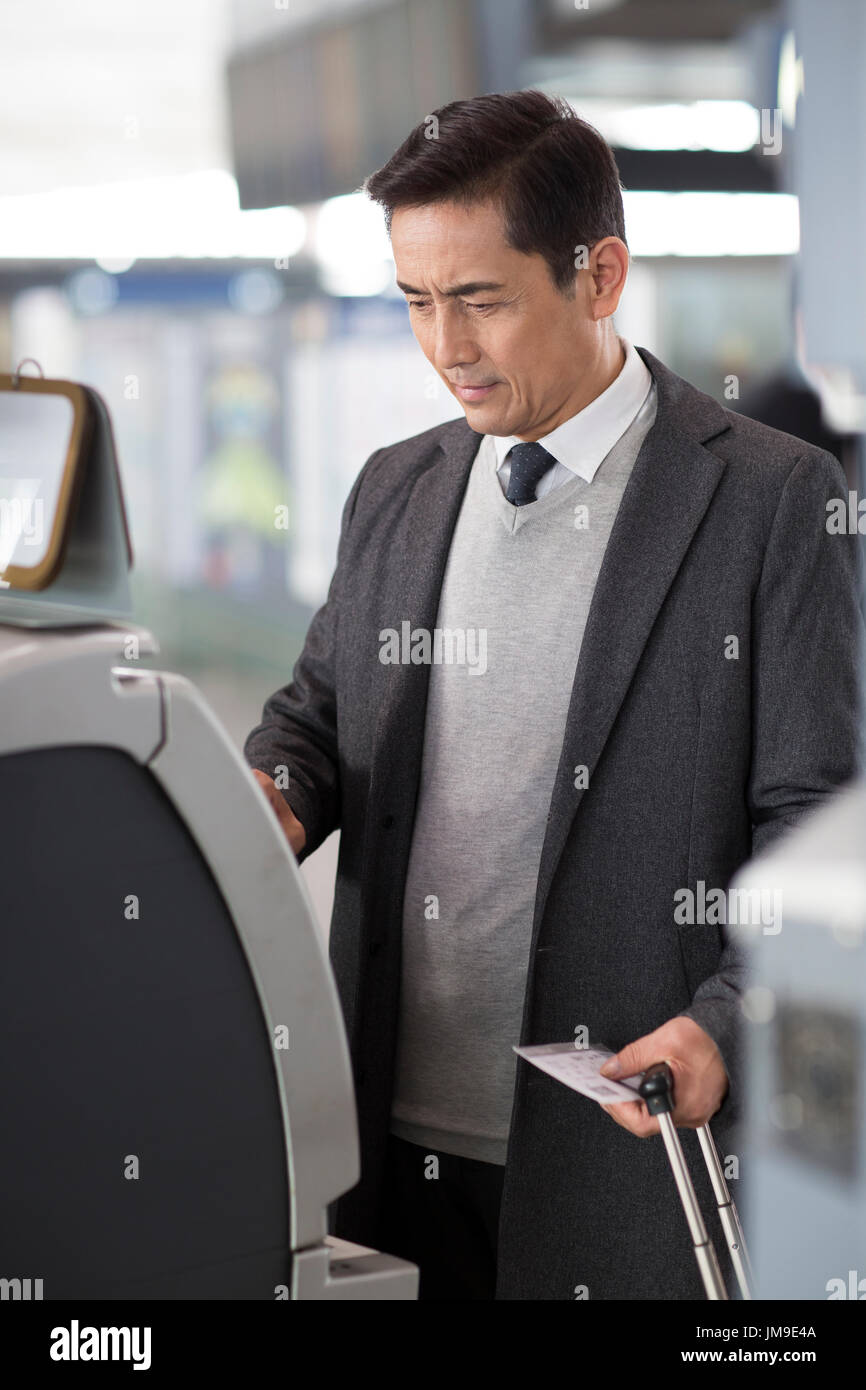 Chinese businessman using ticket machine at the airport Stock Photo - Alamy