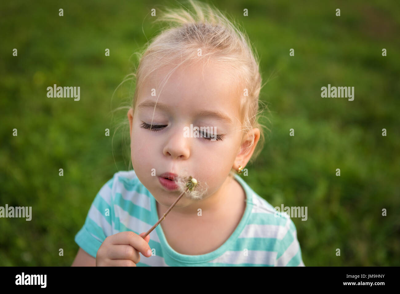 Adorable little blond girl with dandelion flower. Happy kid having fun ...