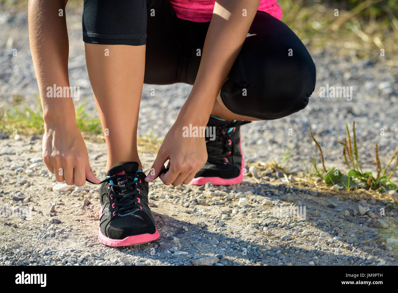 Attractive female runner tying her shoe laces Stock Photo - Alamy