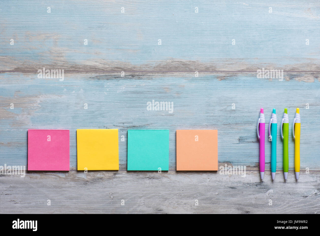 Retro blue wooden table with empty colorful sticky notes and different ...