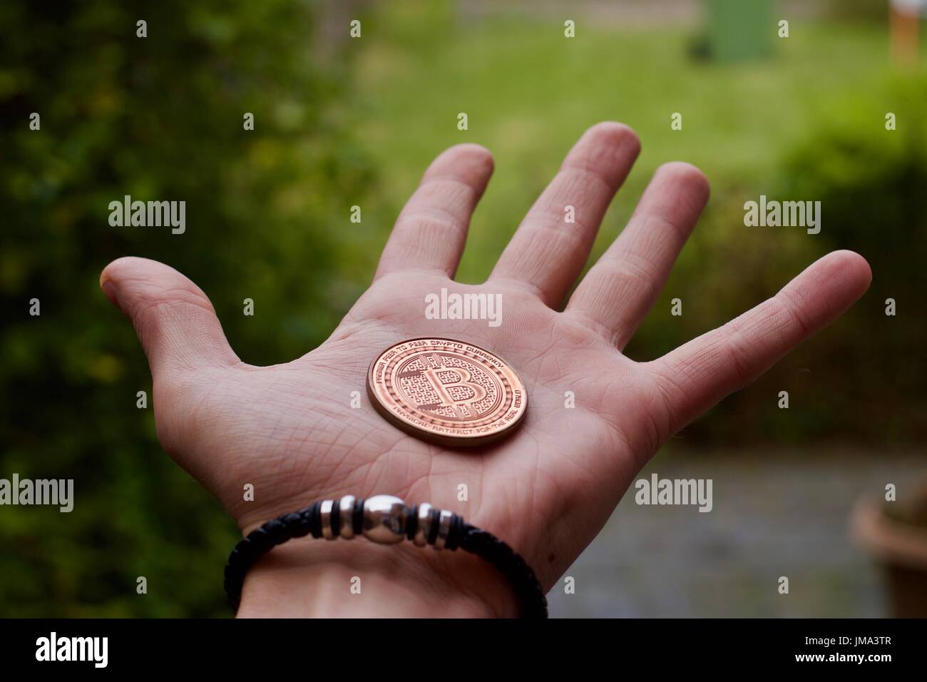 Digital currency physical brass bitcoin coin in man hand with black ...