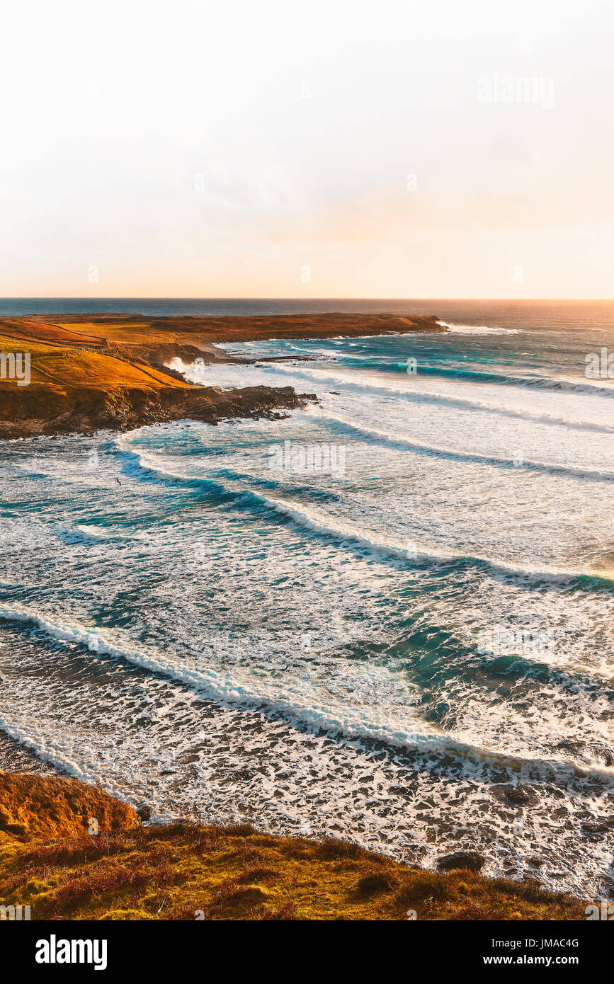 Irish beach during sunset in the summer with a blue sky and waves ...