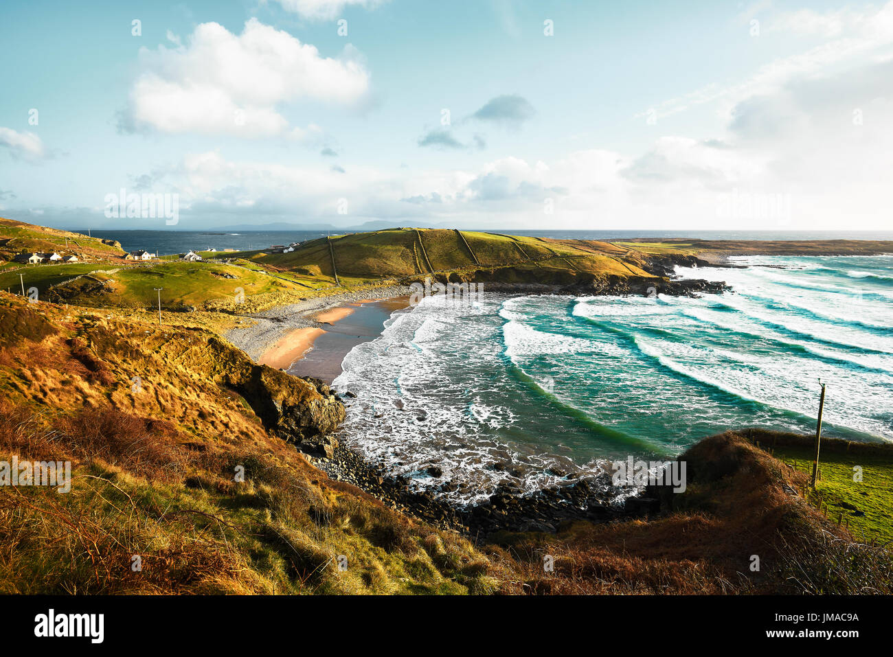 Irish beach during sunset in the summer with a blue sky and waves ...