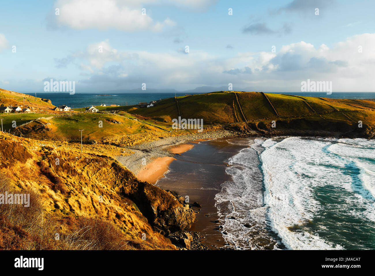 Irish beach during sunset in the summer with a blue sky and waves ...
