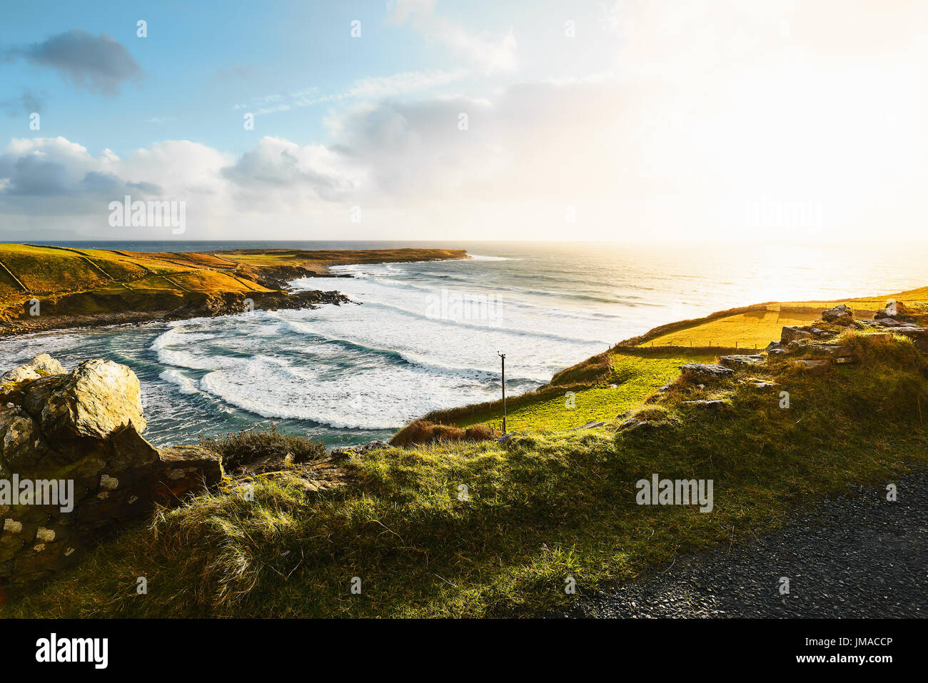 Irish beach during sunset in the summer with a blue sky and waves ...