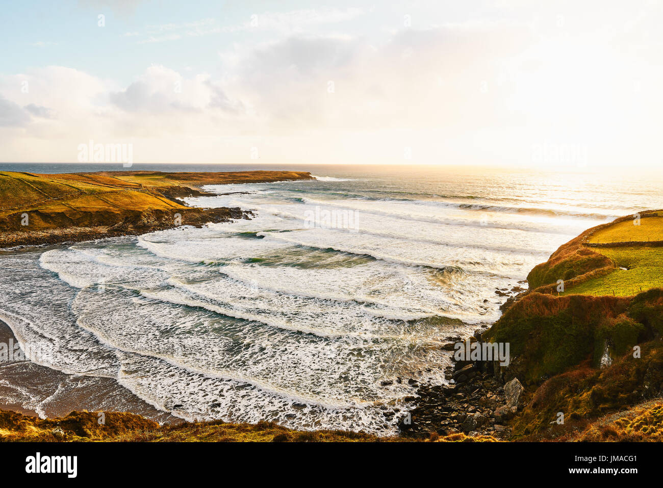 Irish beach during sunset in the summer with a blue sky and waves ...