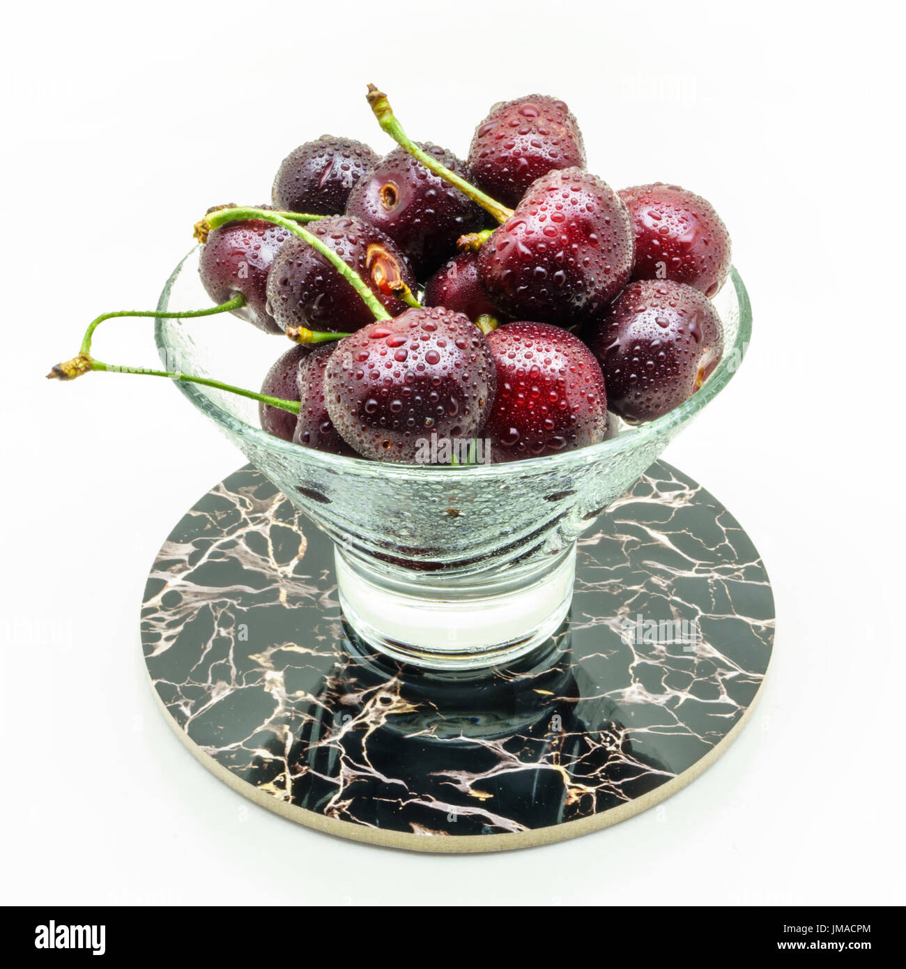 Glass vase on a stand with fresh wet cherries isolated on white ...