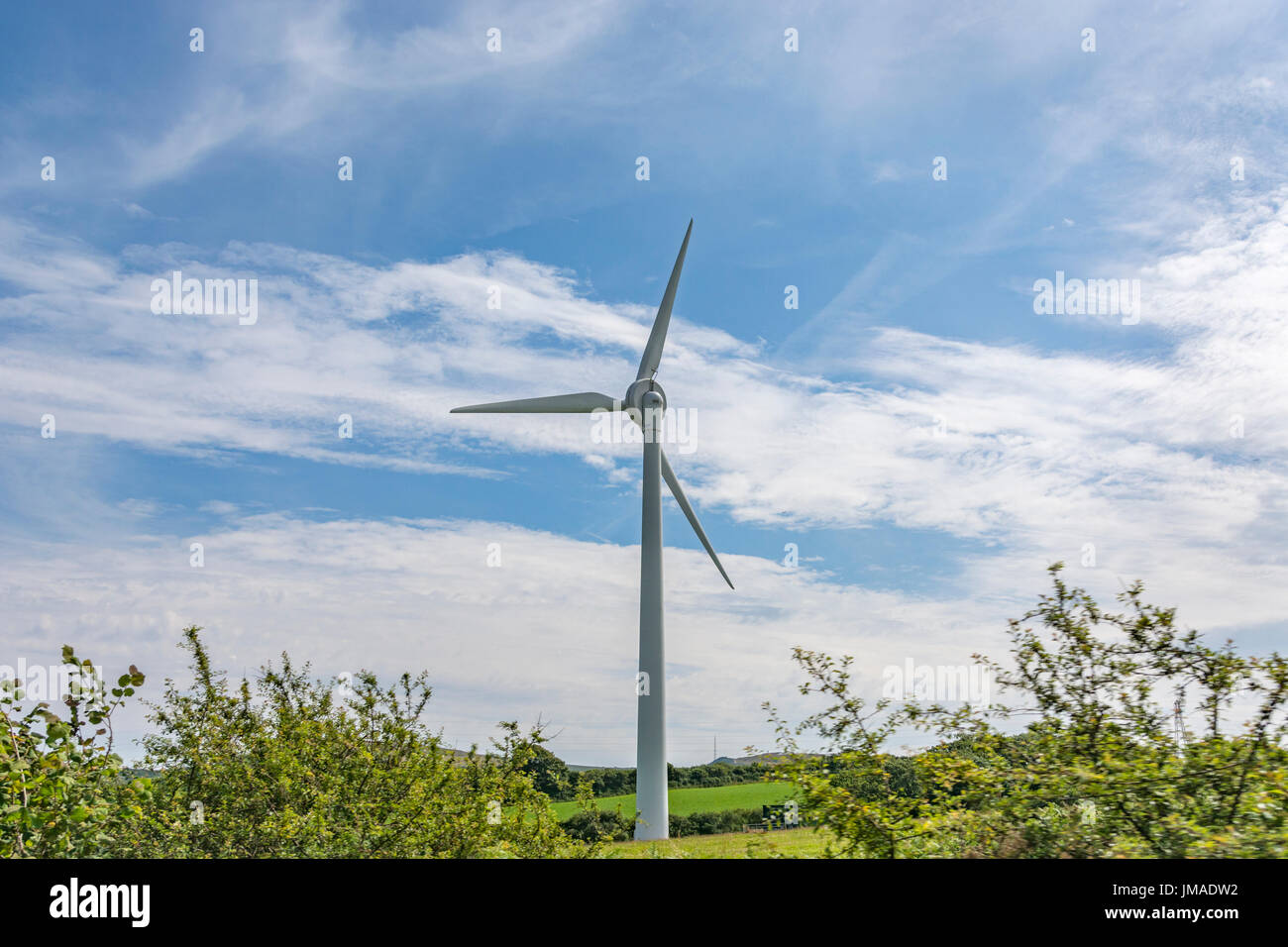 Giant wind turbine / wind generator in a field set against blue sky and ...