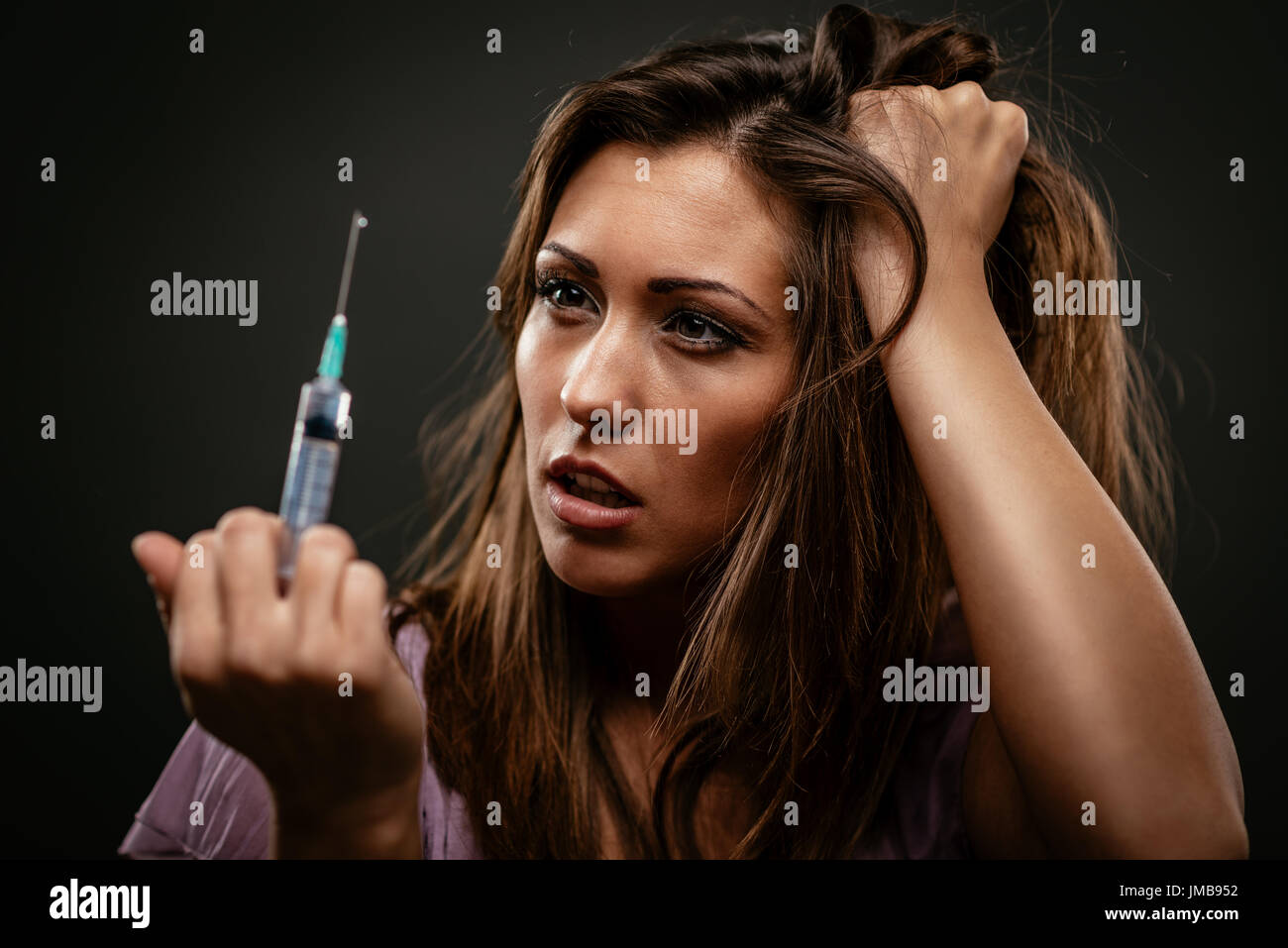 Portrait of a beautiful girl drug addiction. She is holding syringe ...