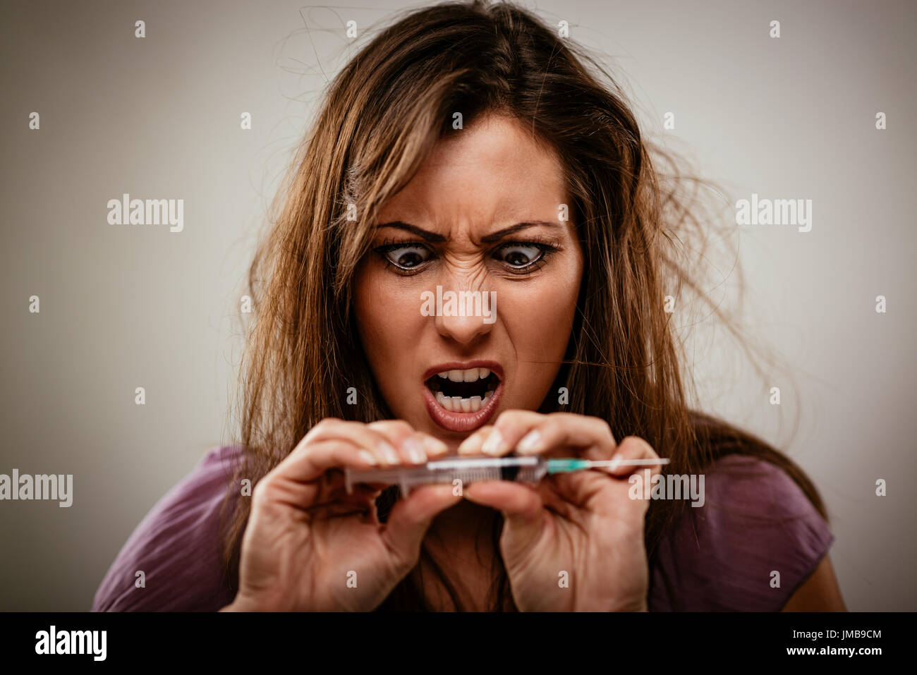 Portrait of a young female drug addiction, holding syringe with drugs ...