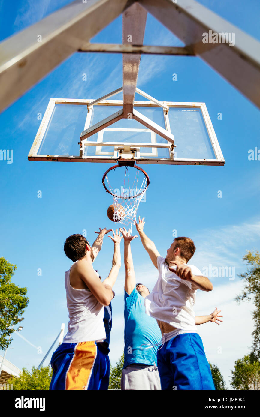 Four basketball players have a training outdoor. They are playing and ...