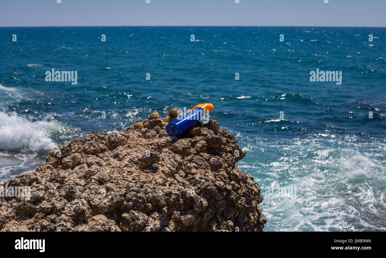 Sun cream sunscreen laying on the beach rocks with dreamy sea and blue ...
