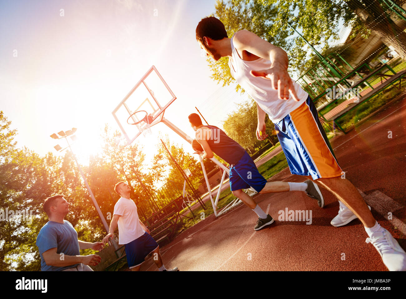 Four basketball players have a training outdoor. They are playing and ...
