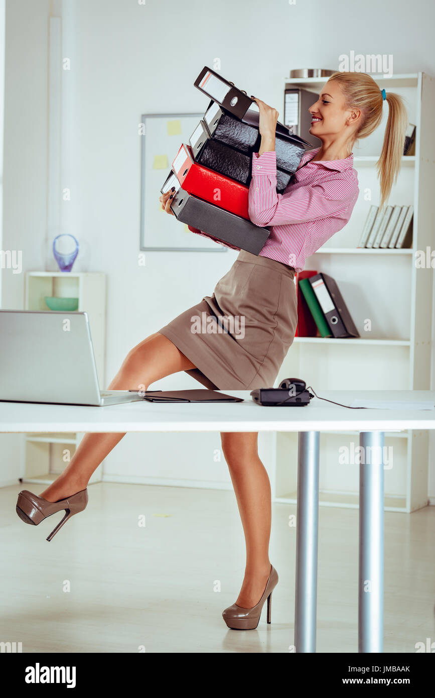 Young smiling business woman wearing a stack of binders in the hands ...